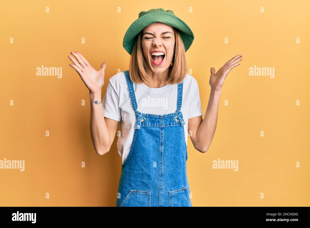 Young caucasian blonde woman wearing denim jumpsuit and hat with 90s ...