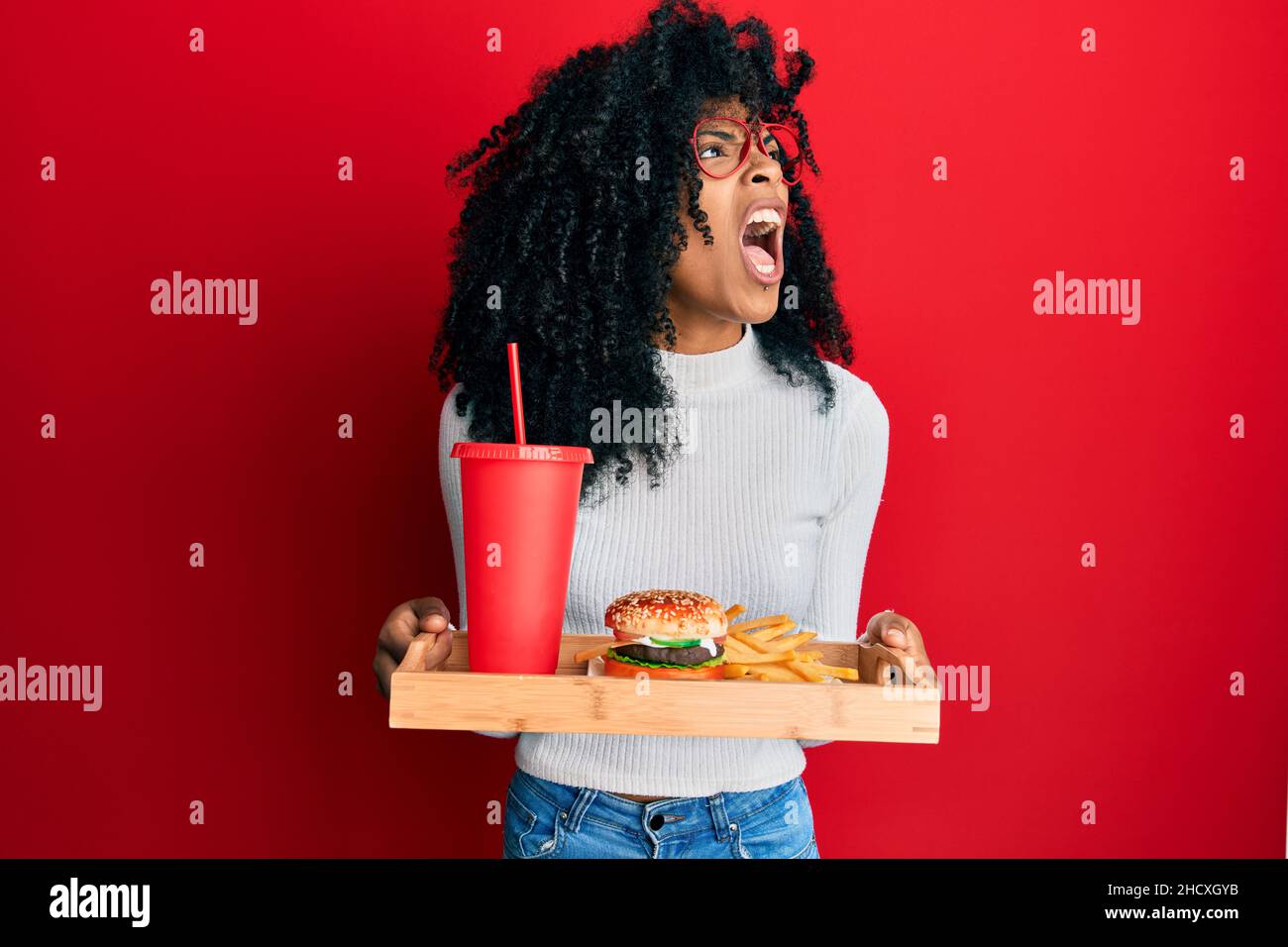 African american woman with afro hair eating a tasty classic burger ...