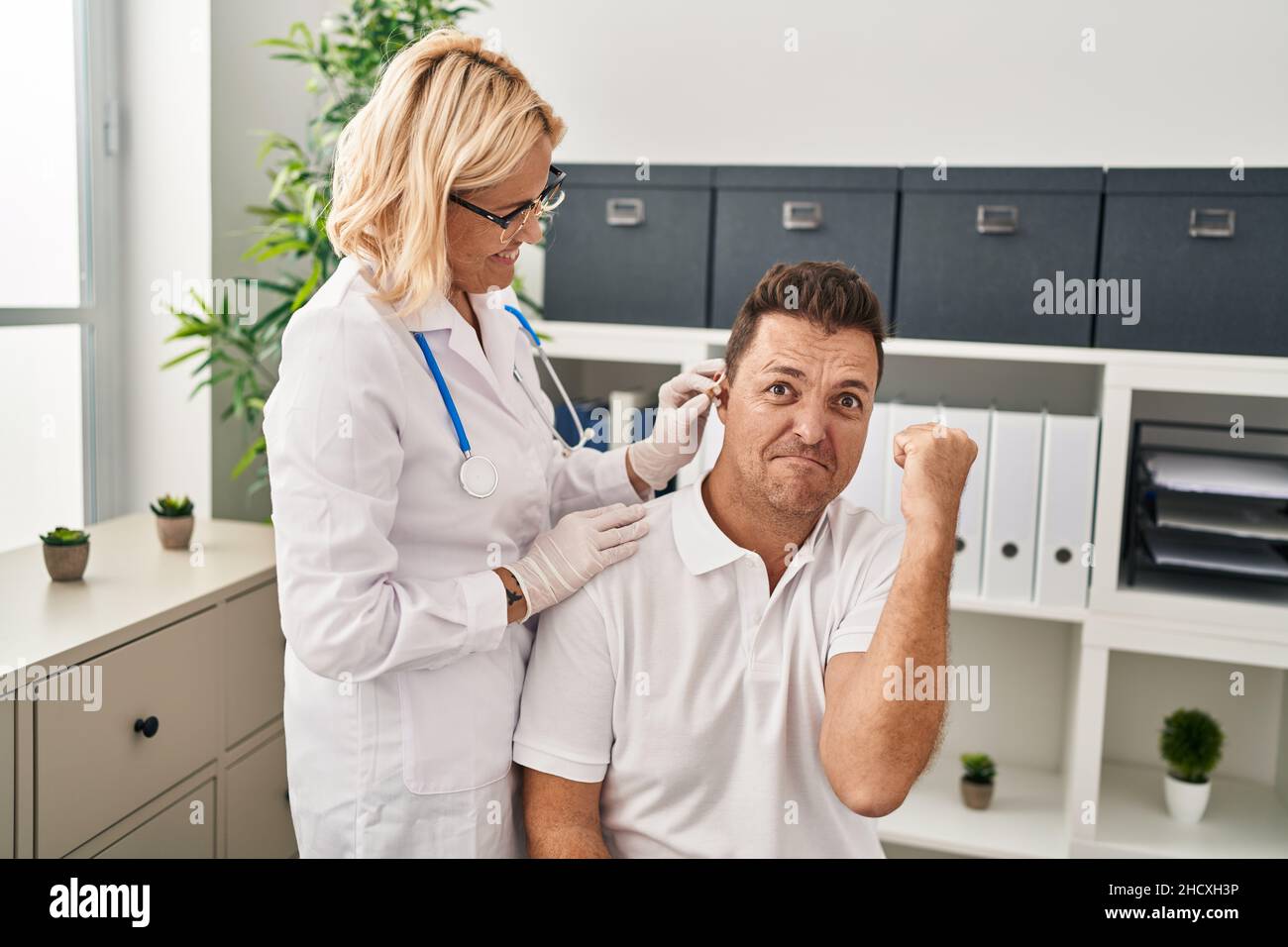 Hispanic man getting medical hearing aid at the doctor annoyed and ...