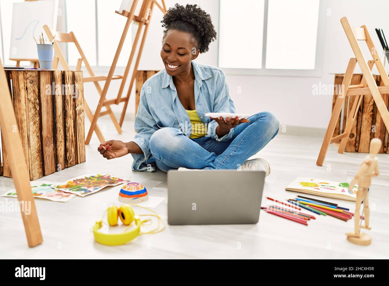 Young african american artist woman using laptop drawing at art studio ...