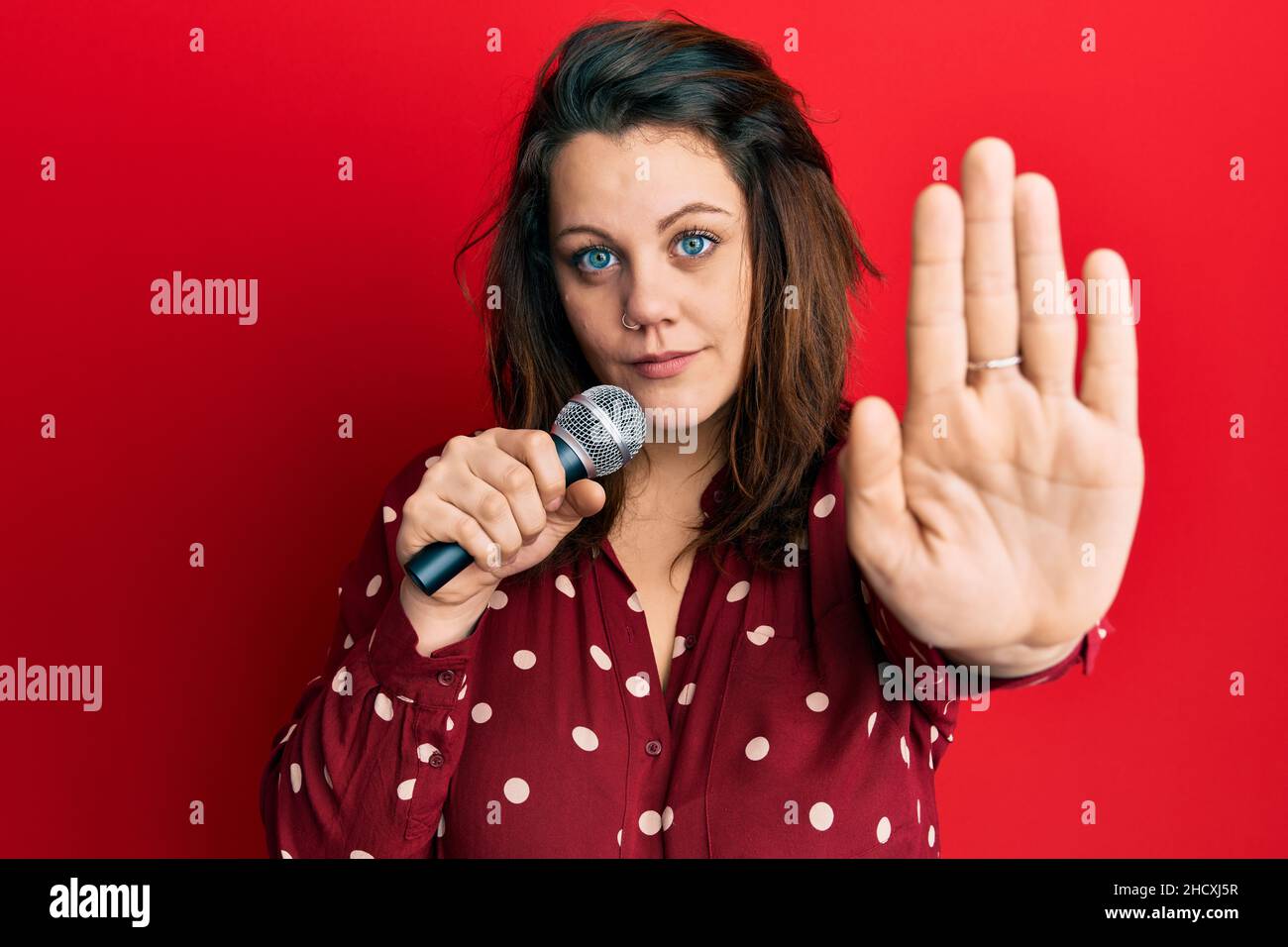 Young caucasian woman singing song using microphone with open hand ...