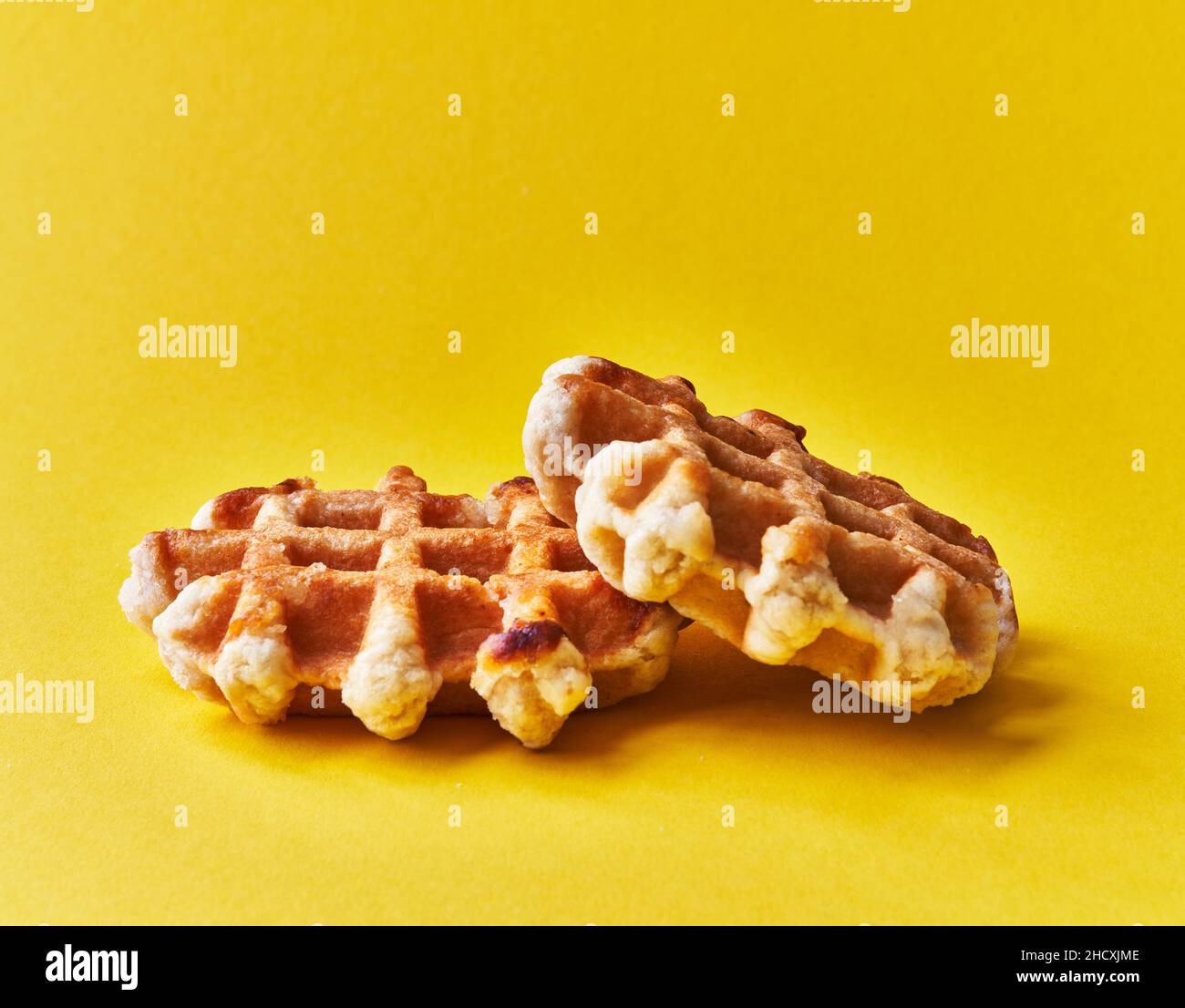 Two delicious waffles over yellow background Stock Photo - Alamy