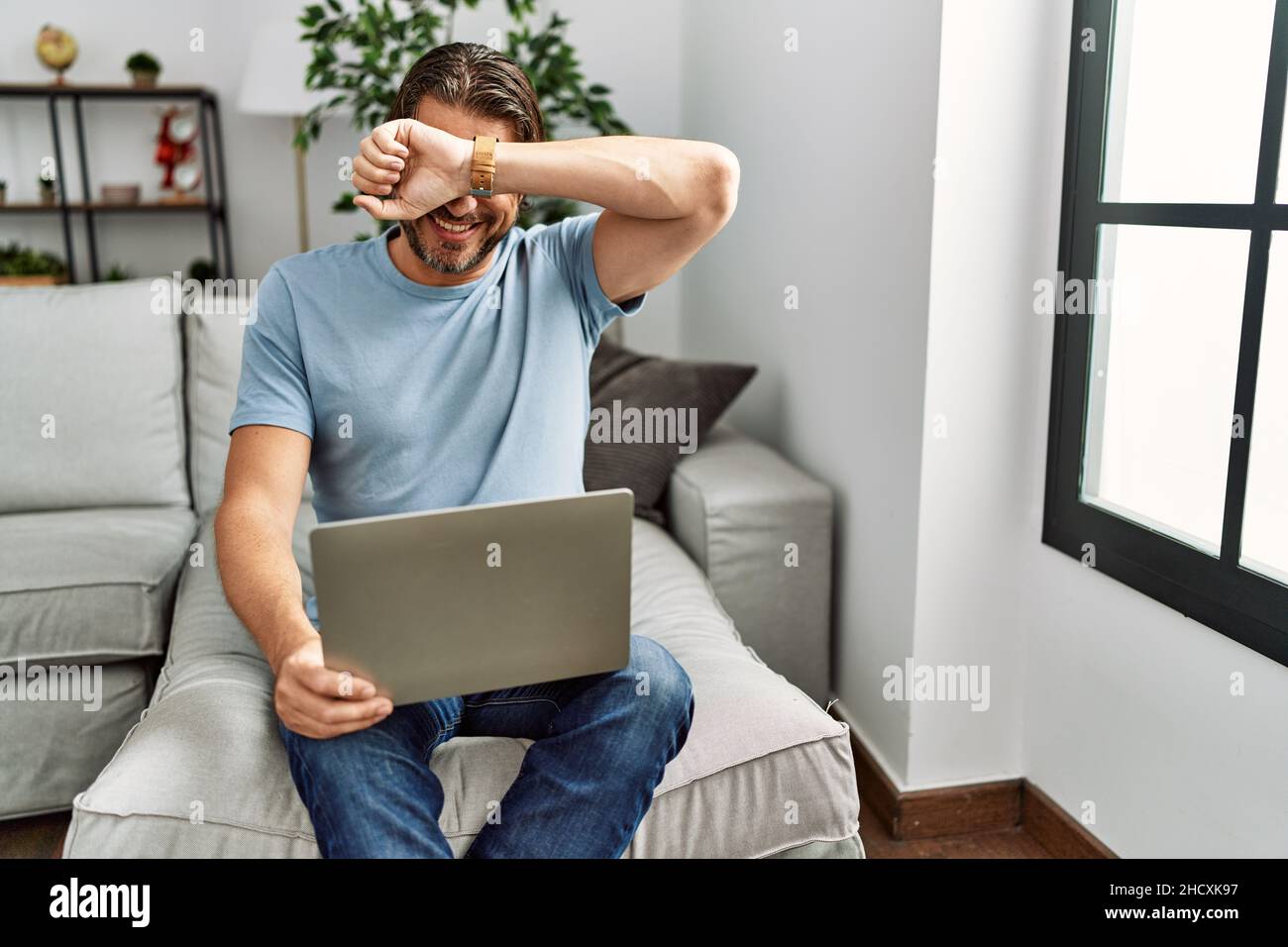 Handsome middle age man using computer laptop on the sofa smiling ...