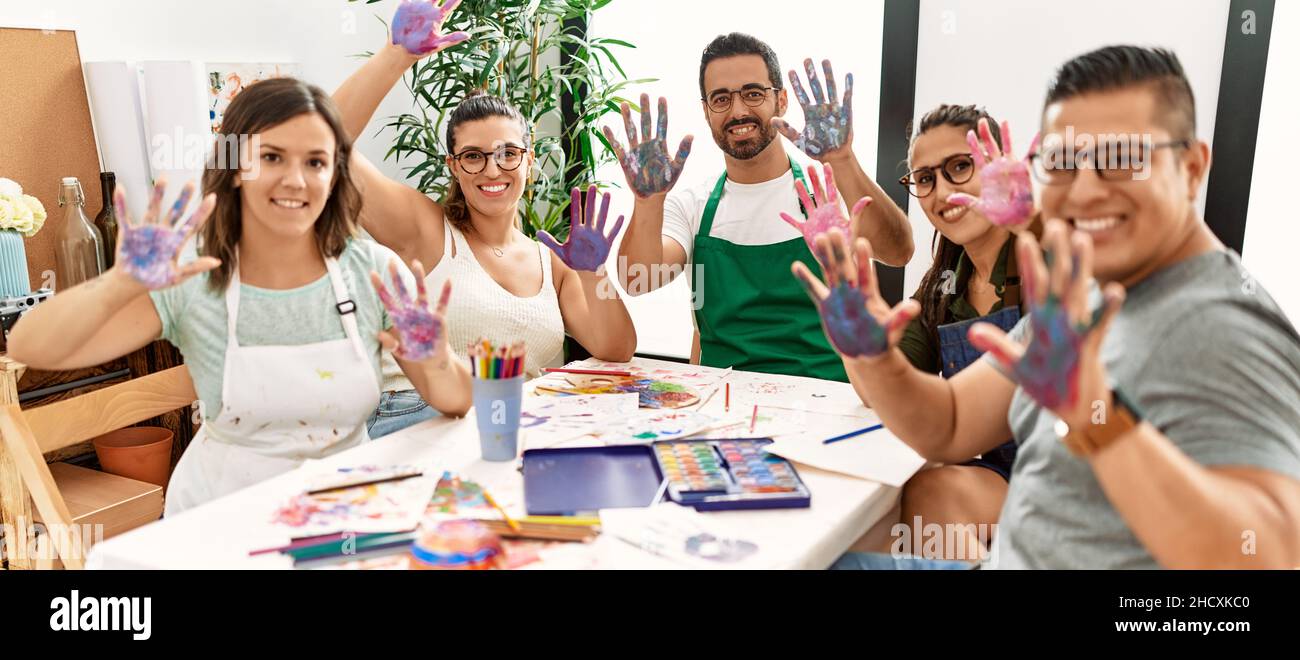 Group of draw students sitting on the table showing painted palm hands ...