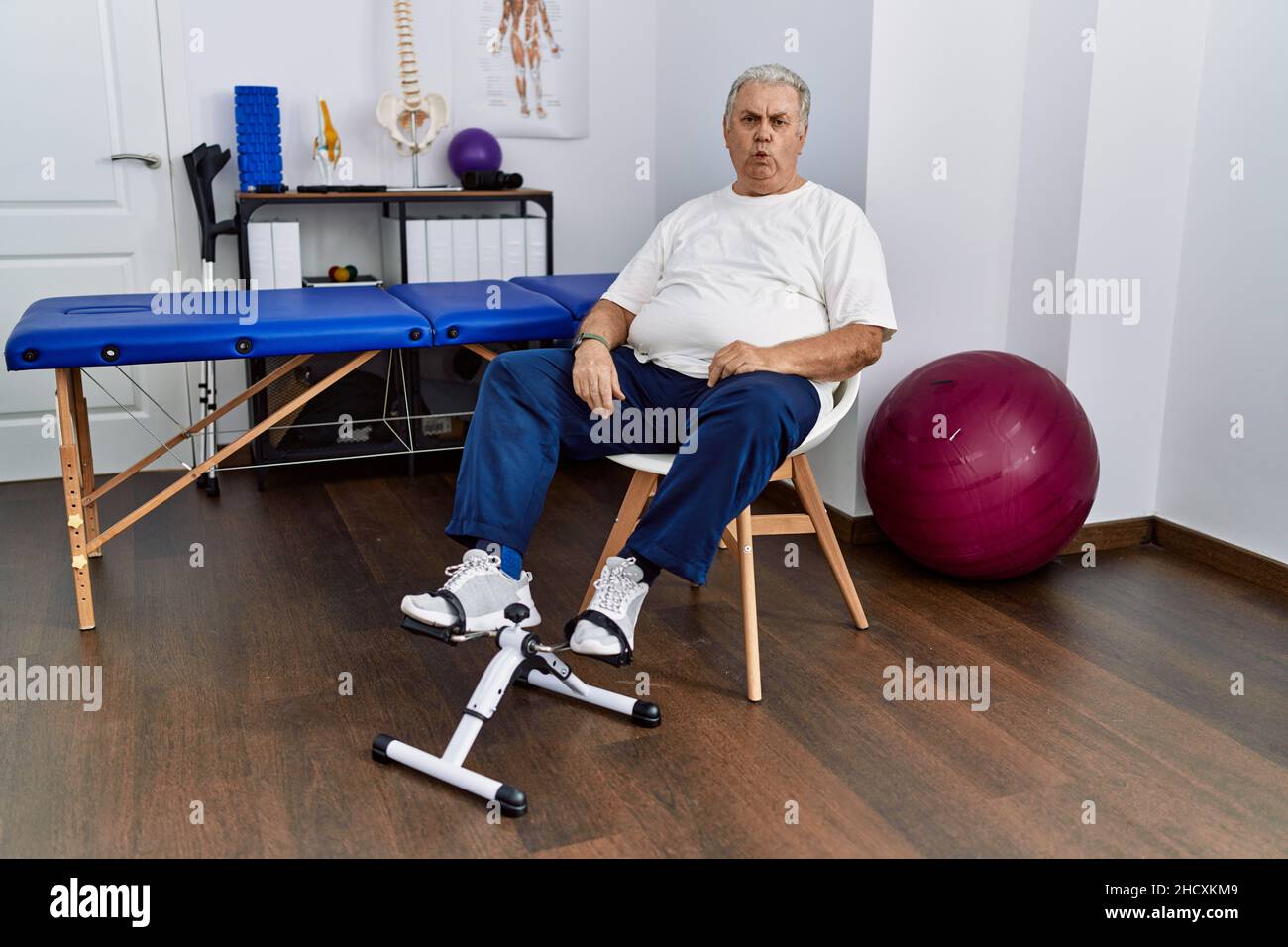 Senior caucasian man at physiotherapy clinic using pedal exerciser ...