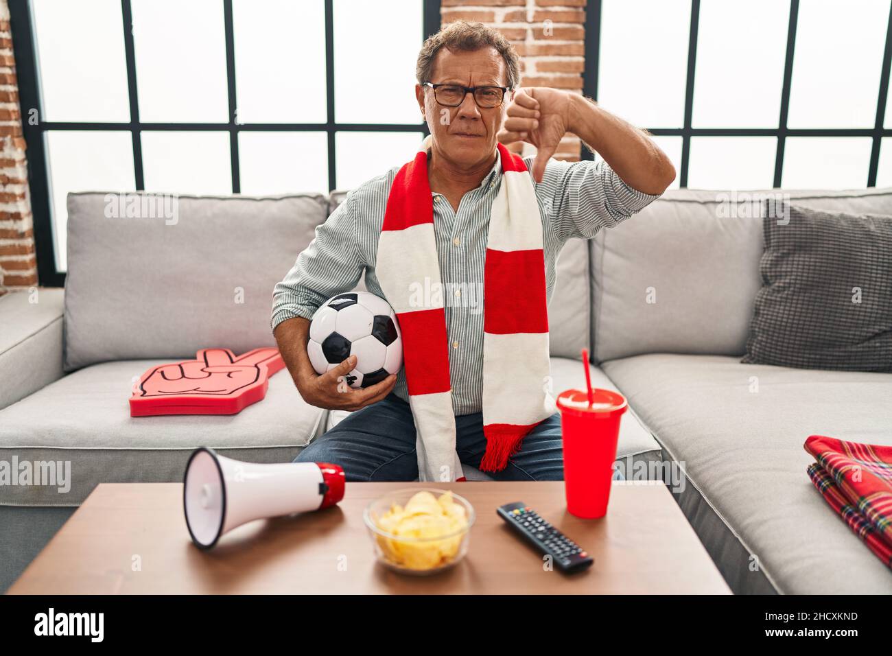 Senior man watching football holding ball supporting team with angry ...