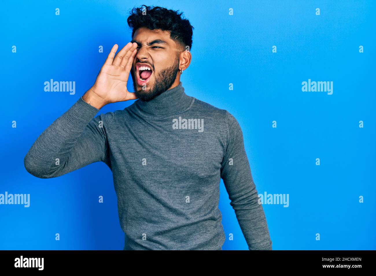 Arab man with beard wearing turtleneck sweater shouting and screaming ...