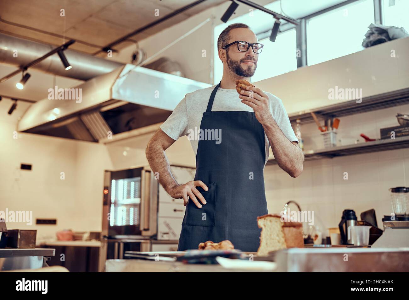 Bearded male baker in apron holding pastry Stock Photo - Alamy