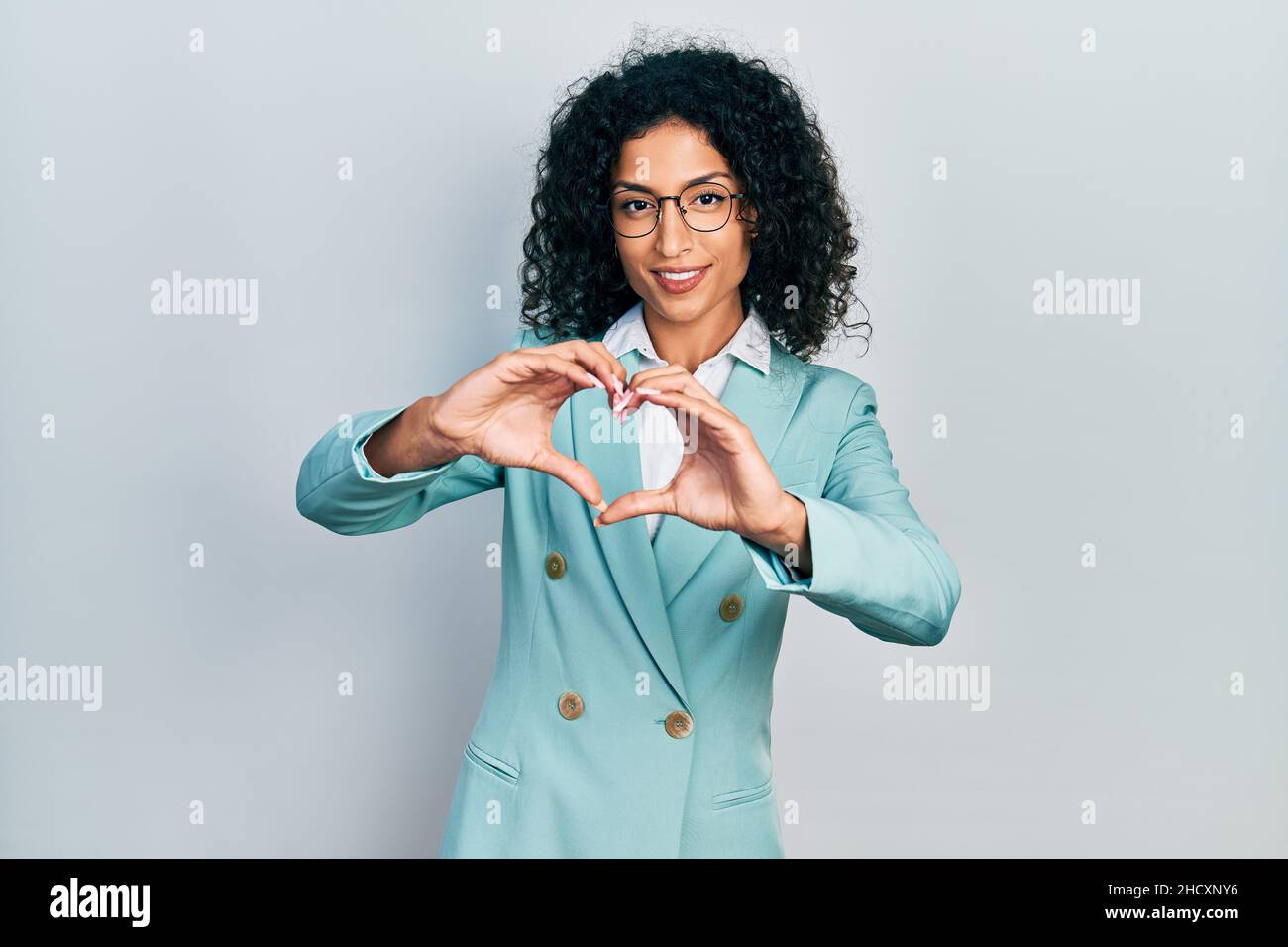 Young latin girl wearing business clothes and glasses smiling in love ...