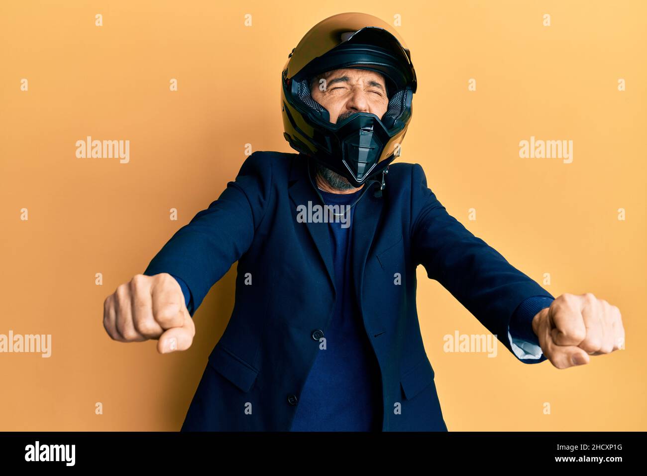 Middle age hispanic man wearing motorcycle helmet doing moto symbol ...