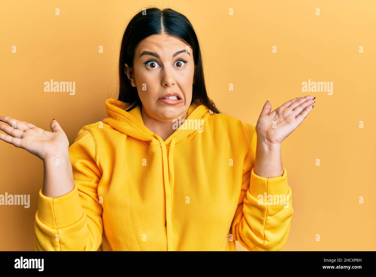 Beautiful brunette woman wearing casual sweatshirt clueless and ...