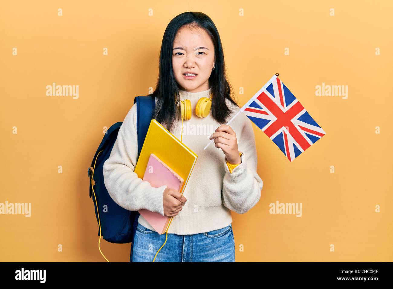 Young chinese girl exchange student holding uk flag clueless and ...