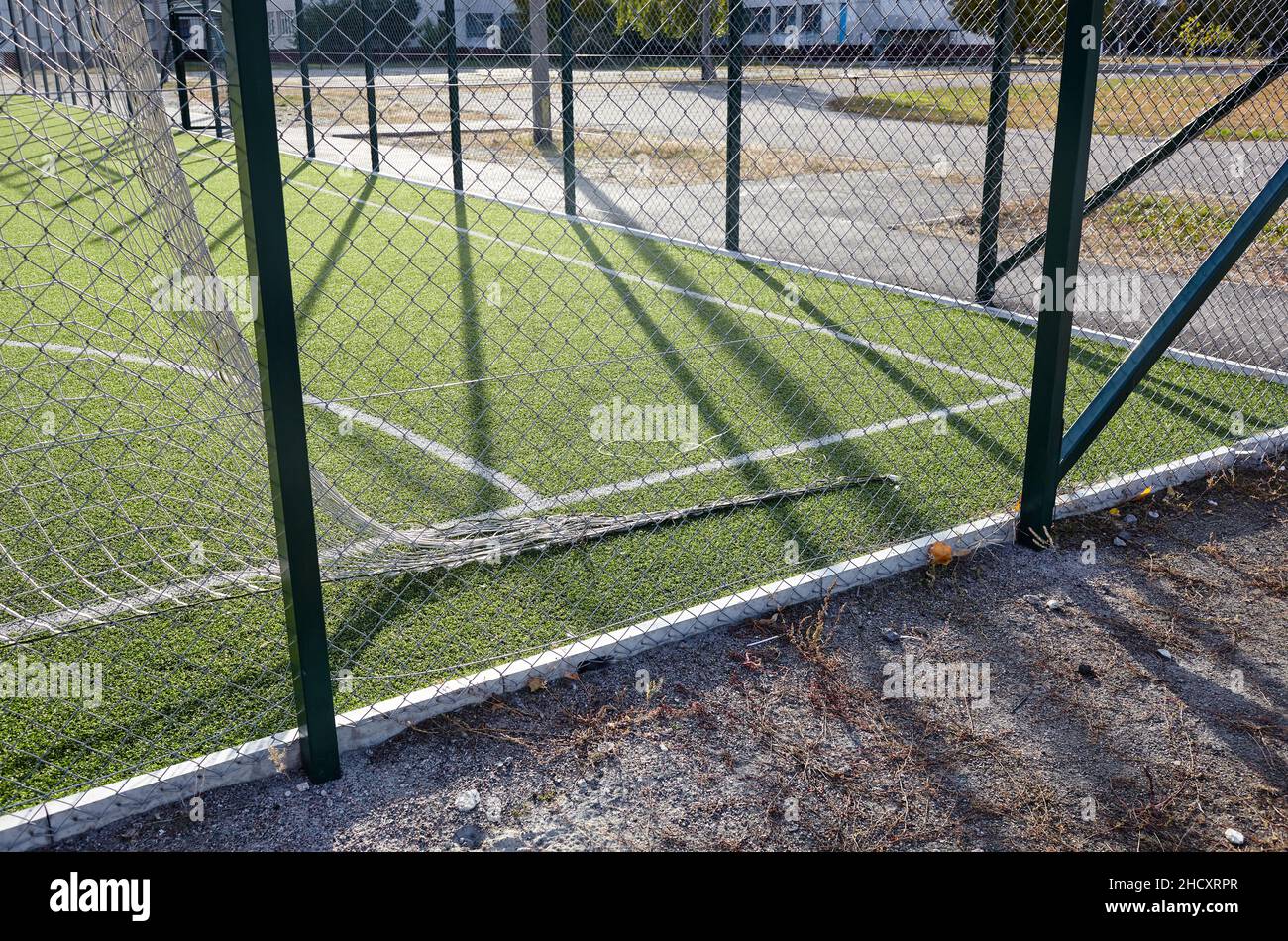 Lawn field for playing football behind the green fence mesh. Close-up ...