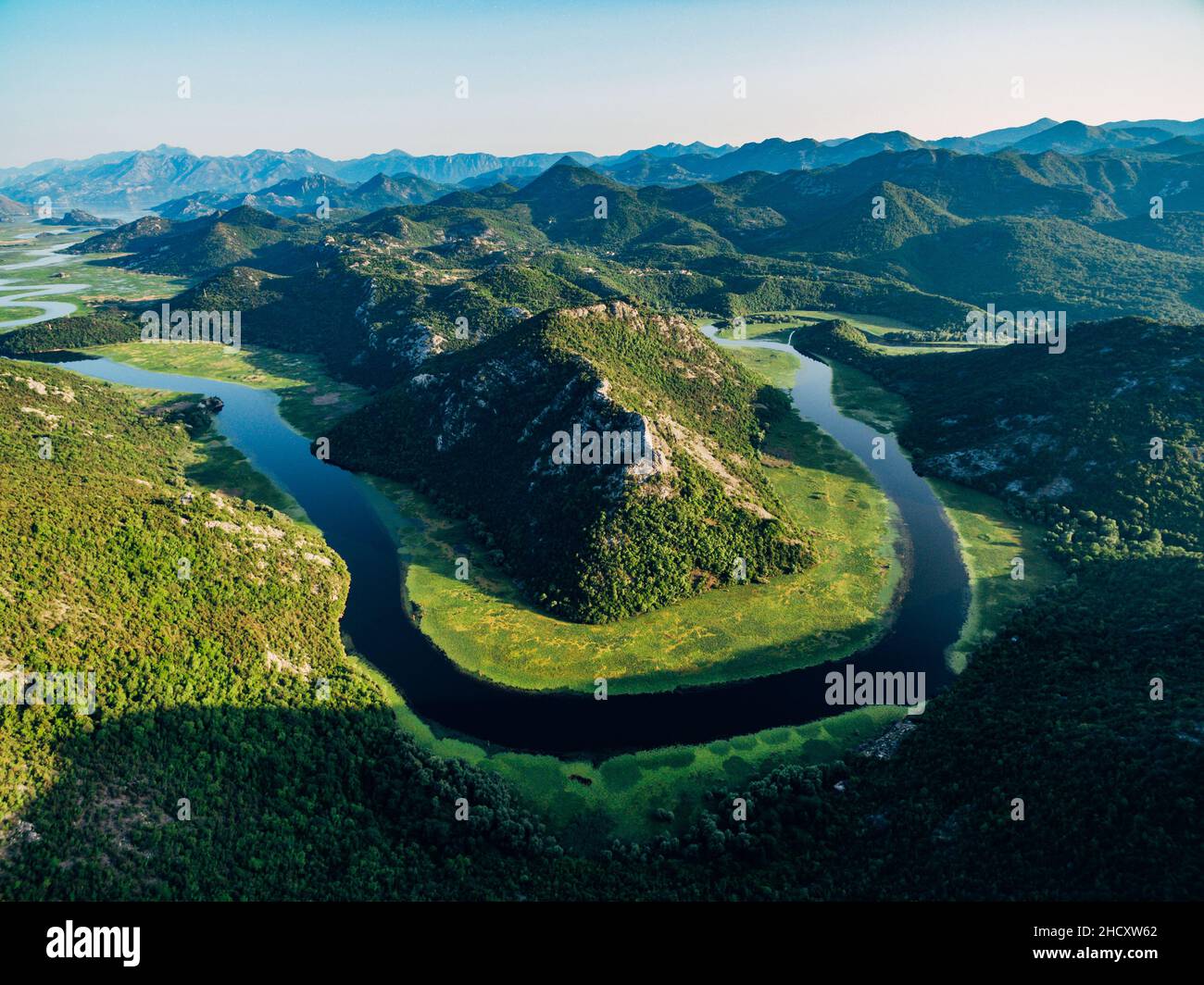 Crnojevica river makes a loop around the green pyramidal mountain Stock ...