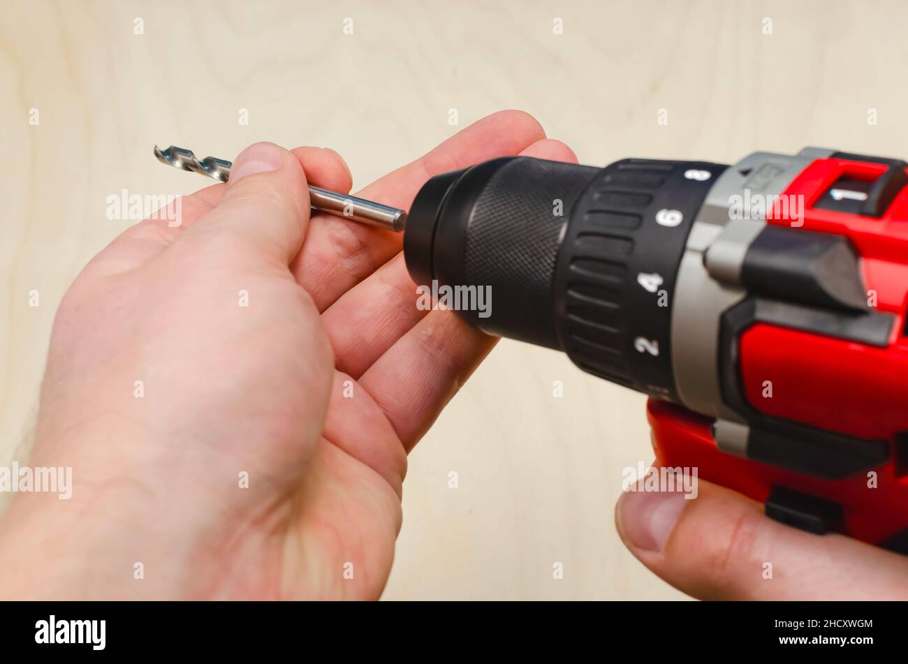 Installs the drill into the drill, hands take the drill and install it ...