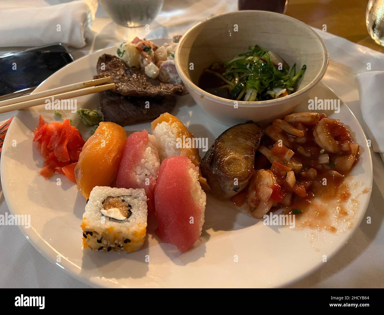 A big white plate with mixed surf and turf food including steak and ...