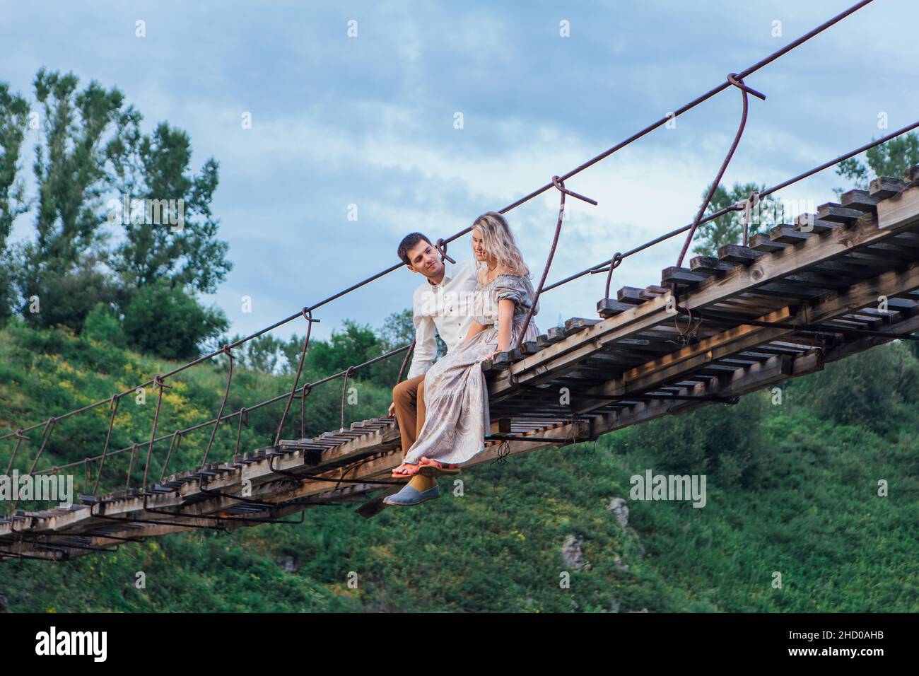 Beautiful young romantic couple sitting and hugging on the suspension ...
