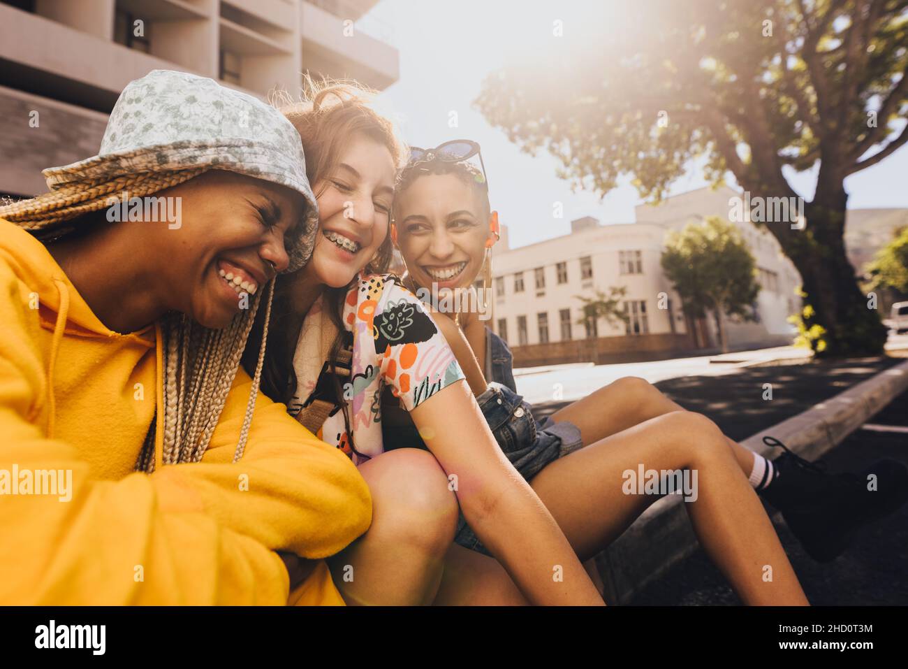 Young female friends having fun in the city. Group of generation z friends laughing cheerfully ...