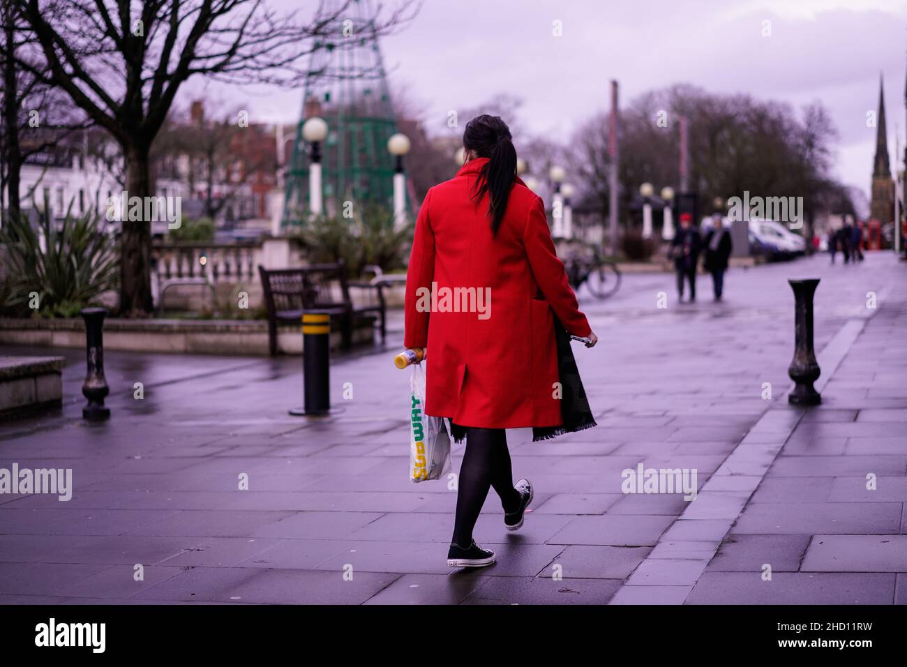 A female in a bright red coat walking Stock Photo - Alamy
