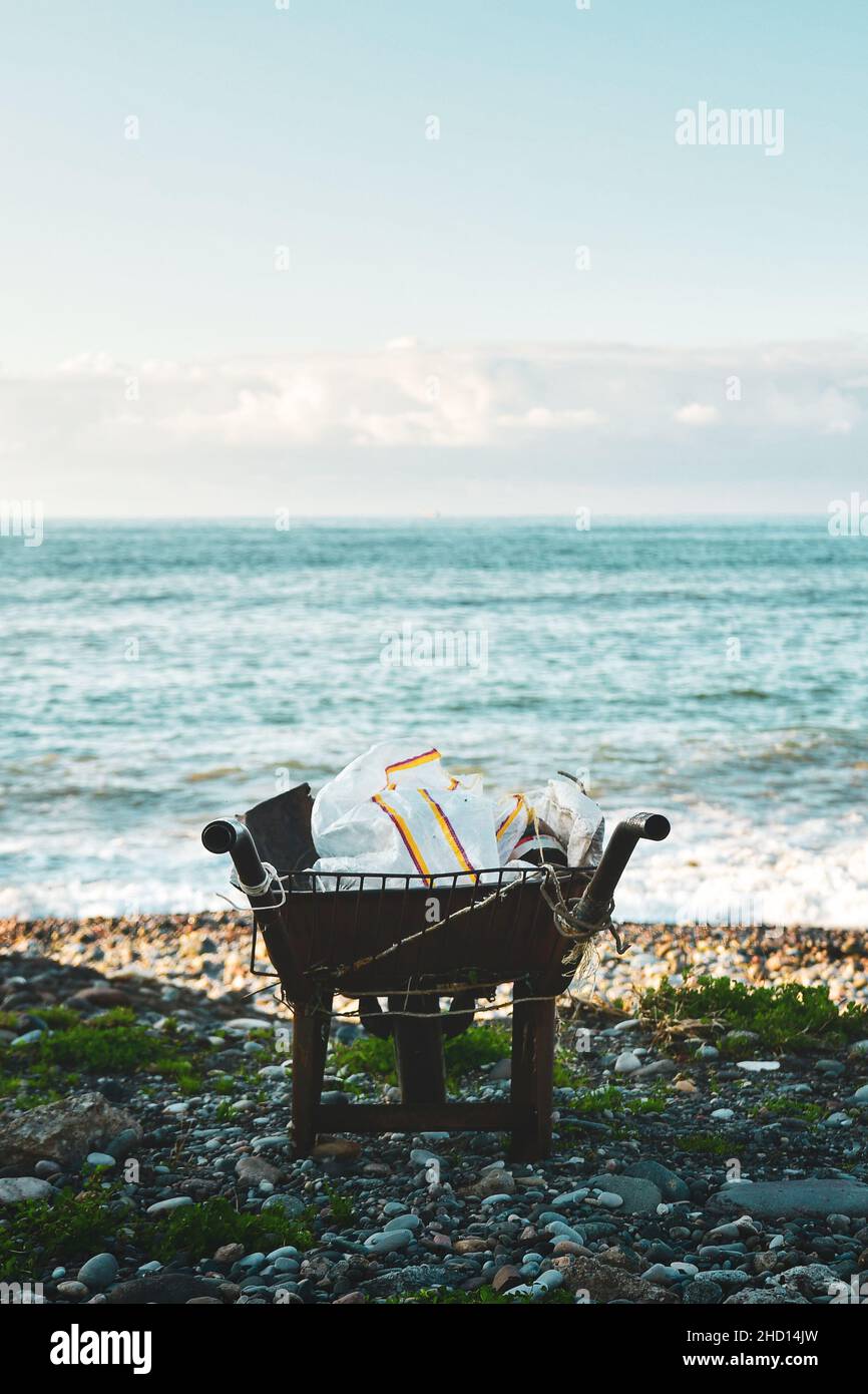 Wheelbarrow full of plastic waste stand on beach with sea panorama ...