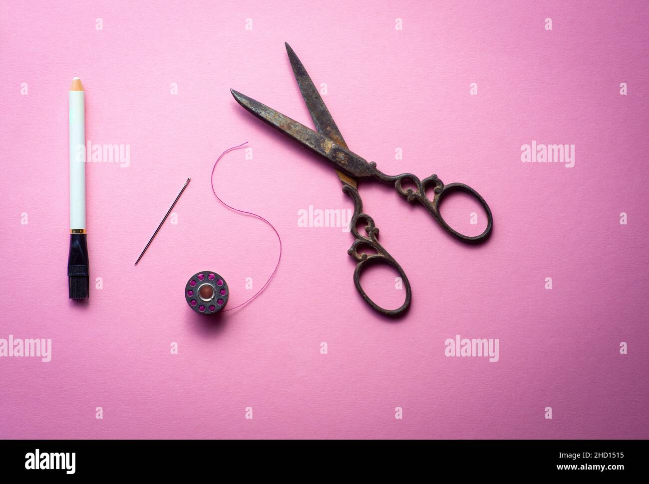 bobbin or spool of thread and scissors with needle for sewing on pink ...