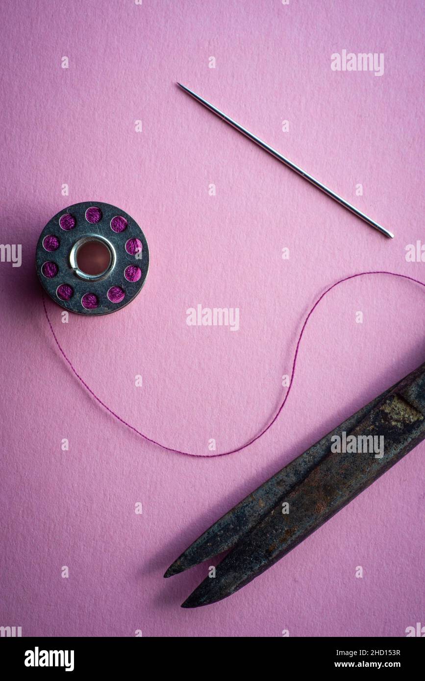 bobbin or spool of thread and scissors with needle for sewing on pink ...