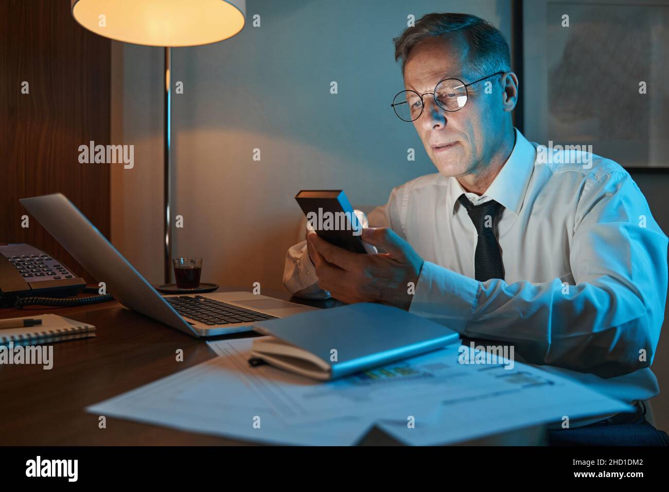 Businessman working overtime in dimly lit hotel room Stock Photo - Alamy