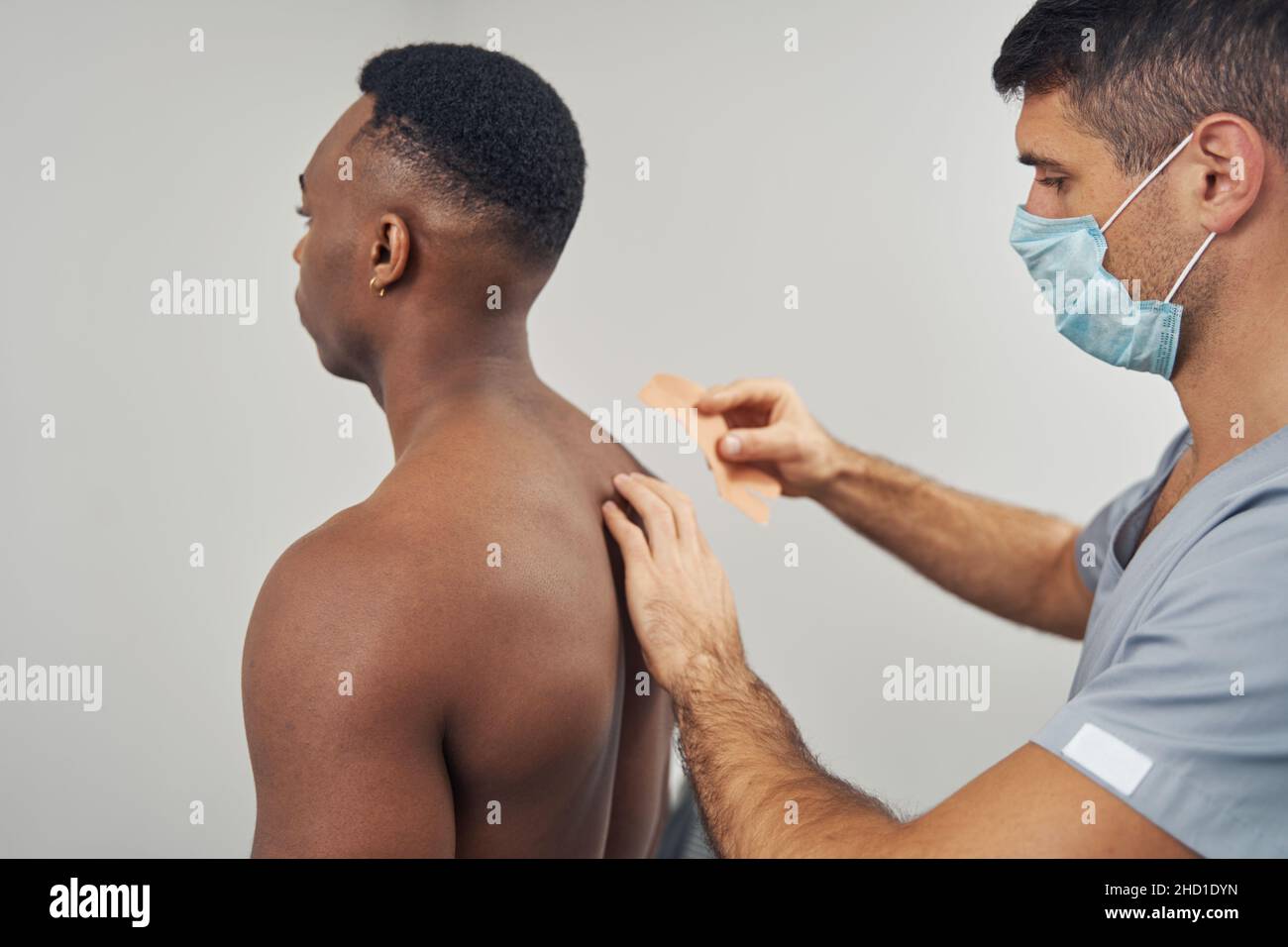 Doctor treating upper back pain using kinesiology taping technique ...