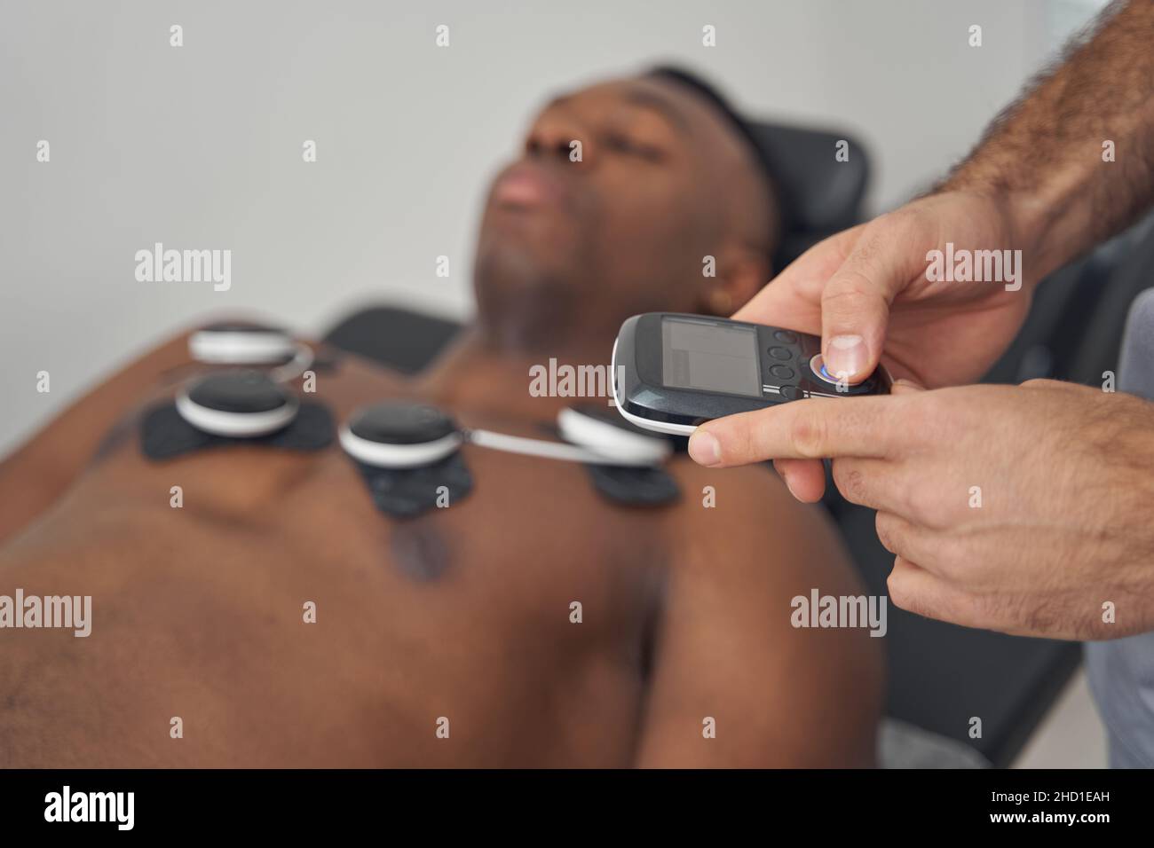 Doctor using EMS device on young man pectorals Stock Photo - Alamy