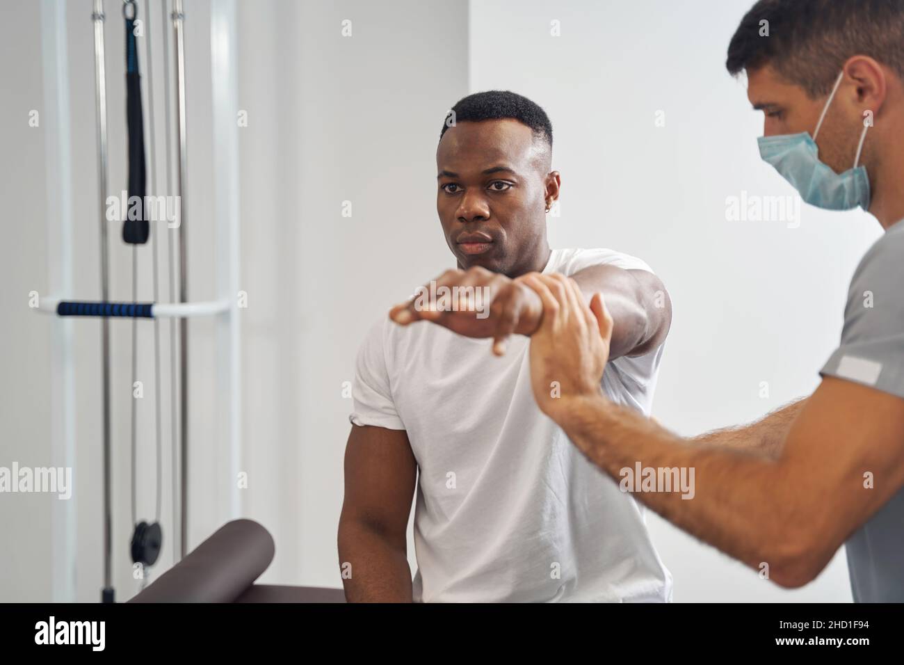 Concentrated physiotherapist assessing muscle strength of young man ...