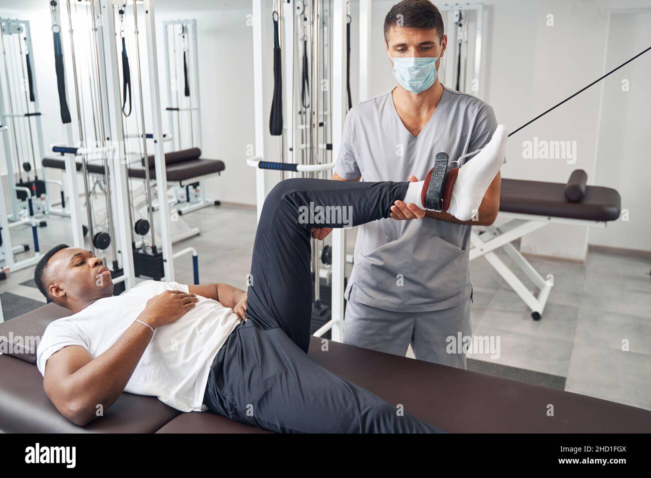 Man performing leg exercise assisted by certified physiatrist Stock ...