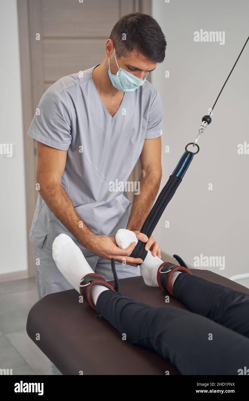 Focused doctor preparing male for strength exercise Stock Photo - Alamy