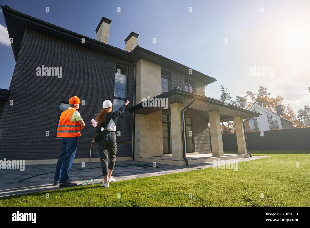 Female designing engineer standing with construction worker outside ...