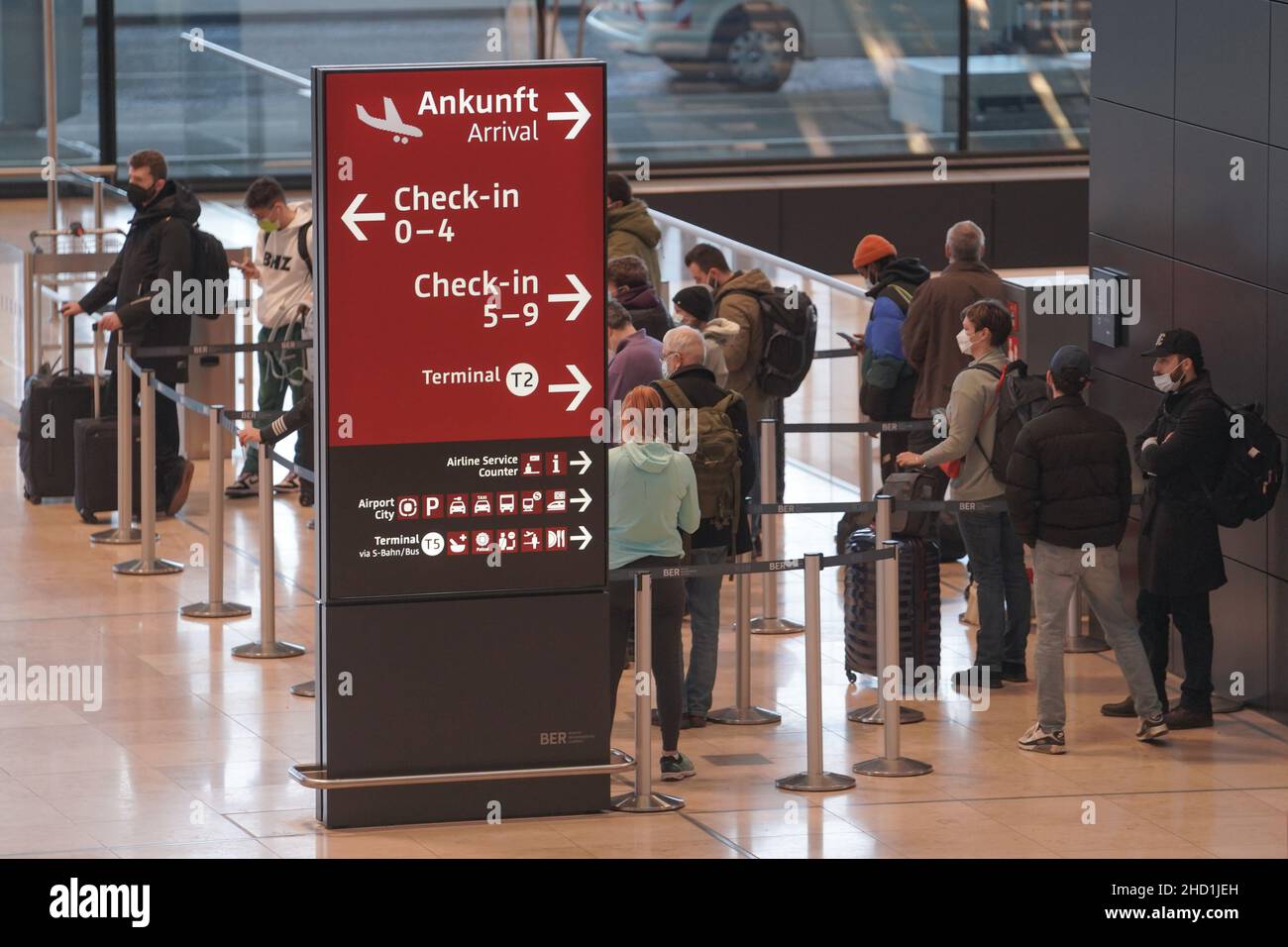 02 January 2022, Brandenburg, Schönefeld: Travellers stand in a queue ...