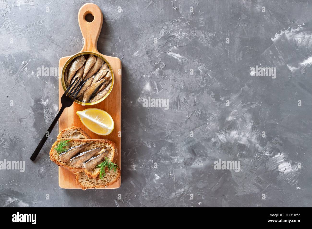 Smoked sprat with oil in an open tin can and sandwiches with fish on a ...