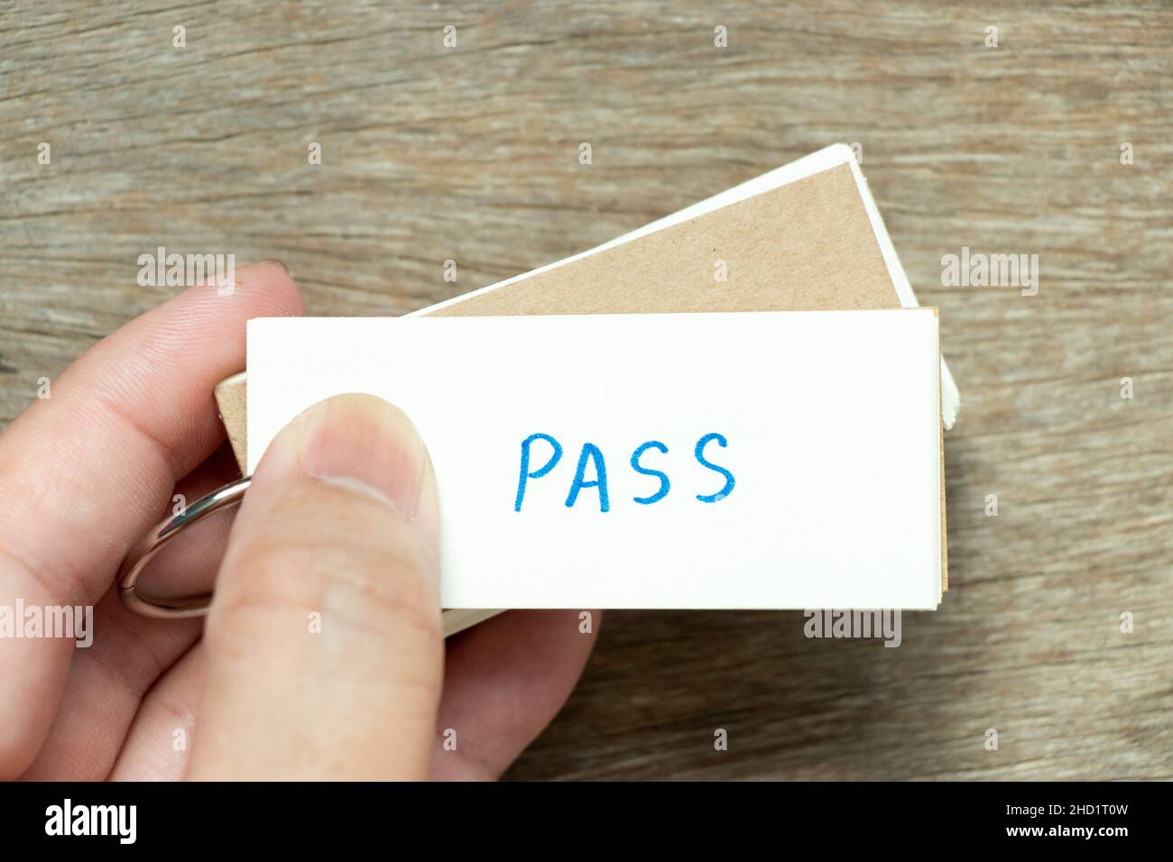 Man hold the flash card with handwriting word pass on wood background ...