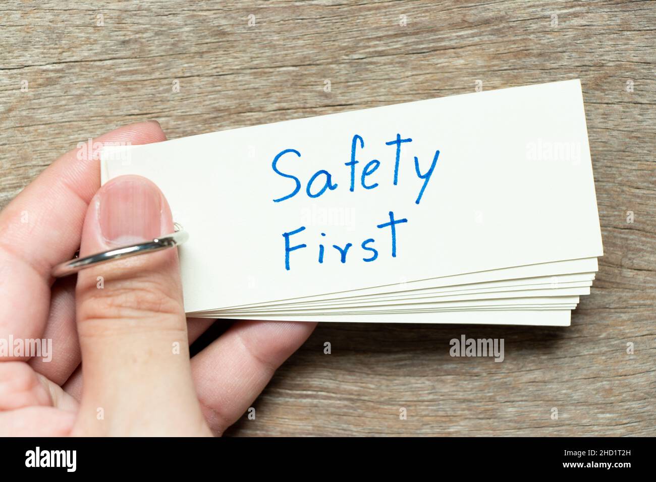Man hold the flash card with handwriting word safety first on wood ...