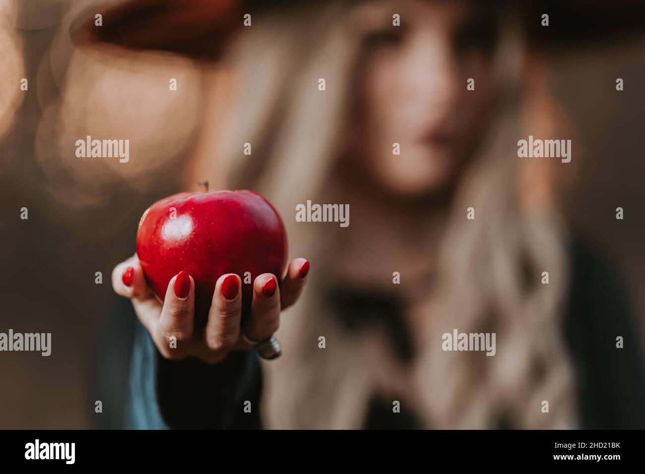 Witch woman in black offers red apple as symbol of temptation, poison ...