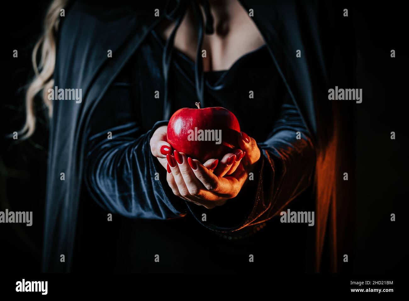 Witch woman in black offers red apple as symbol of temptation, poison ...