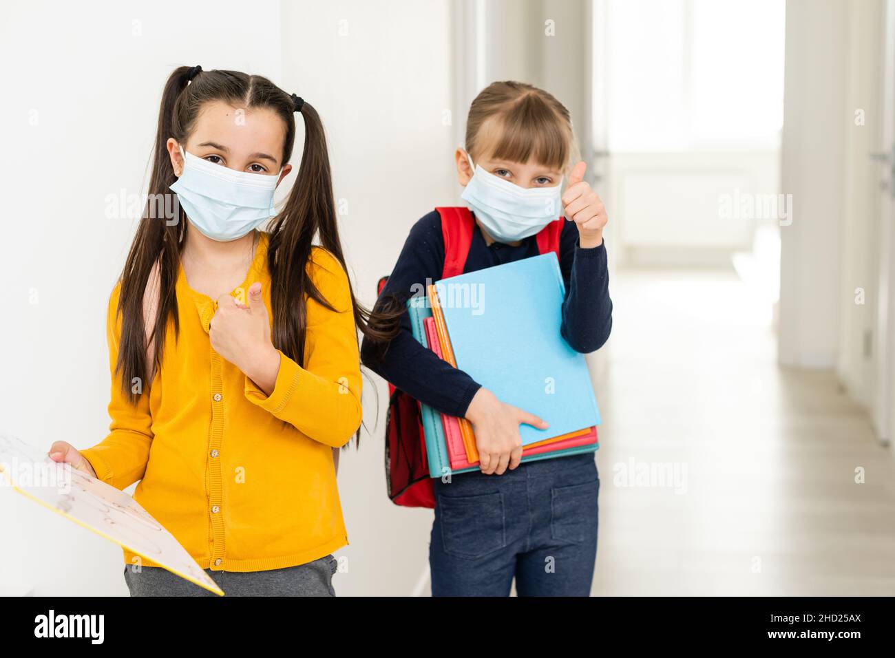 Cute little girls of primary hug each other with the mask on. School ...