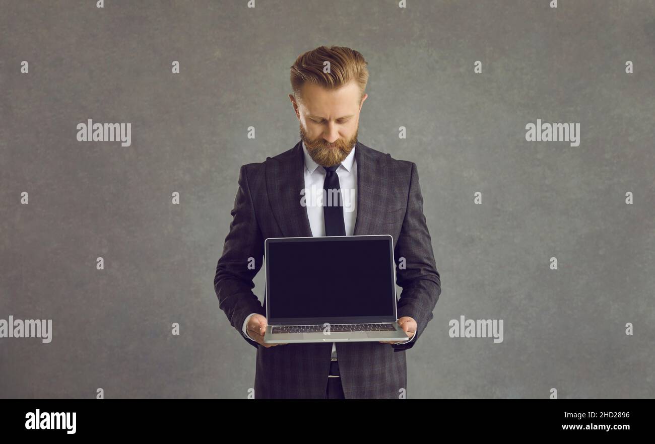 Studio shot businessman shows laptop black screen blank screen monitor ...