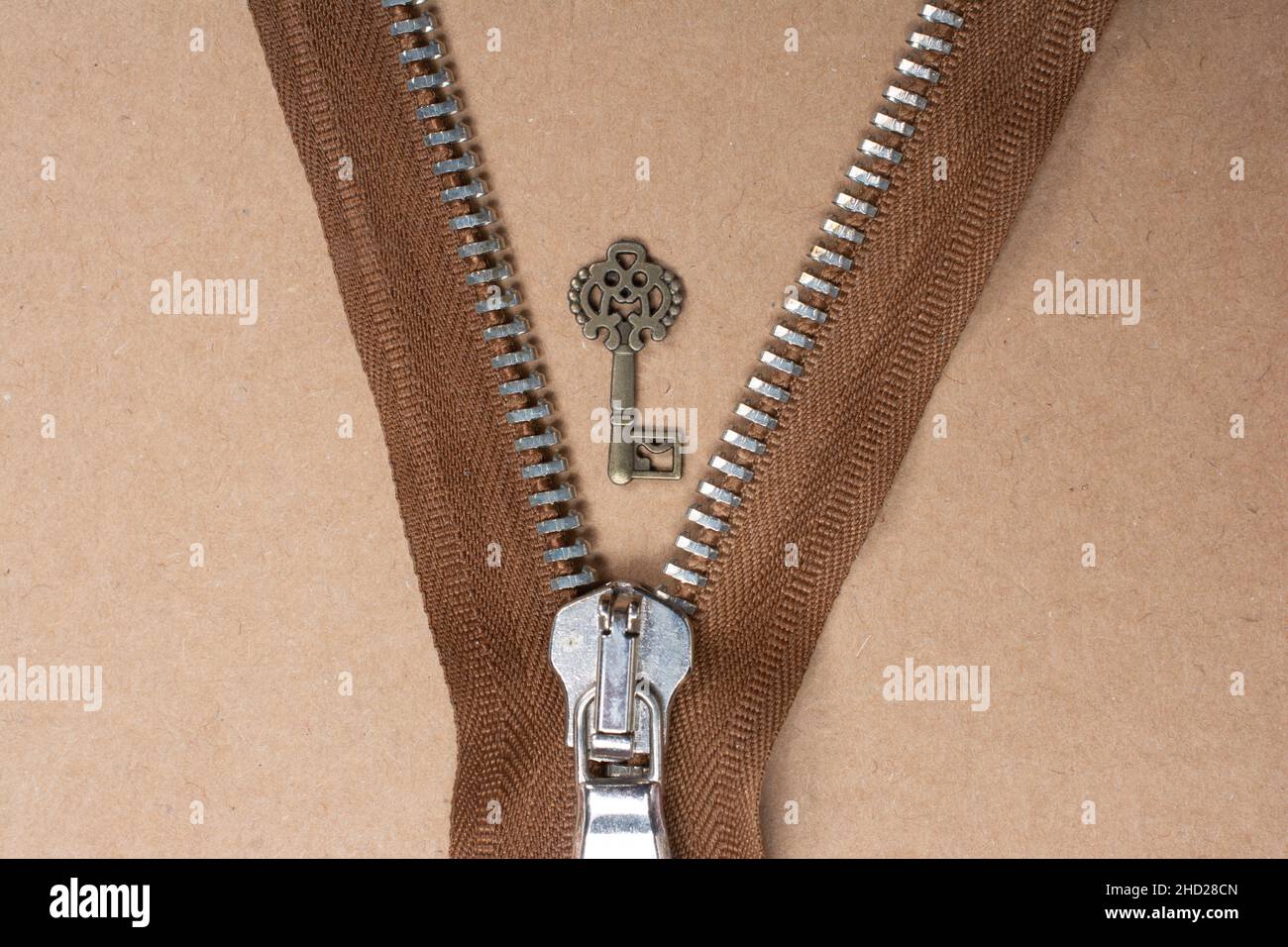 Brown background with an opening zipper and a key Stock Photo - Alamy