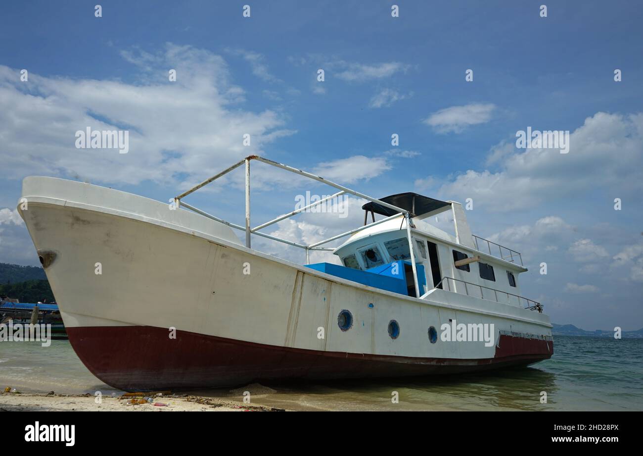 A white ship is being repaired on the shore with small ships sailing in ...