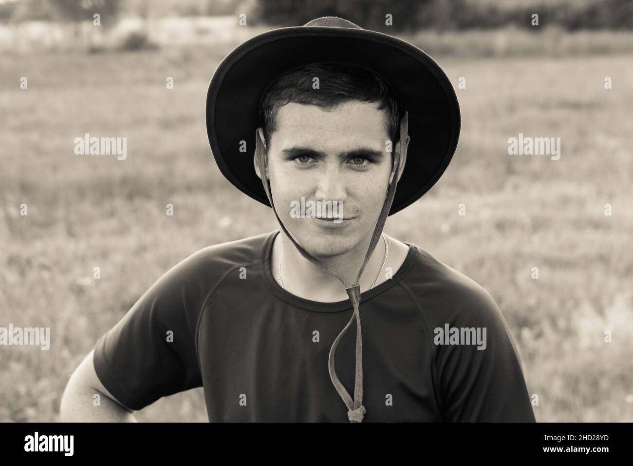 Closeup portrait of millennial man with cowboy hat, standing on nature ...