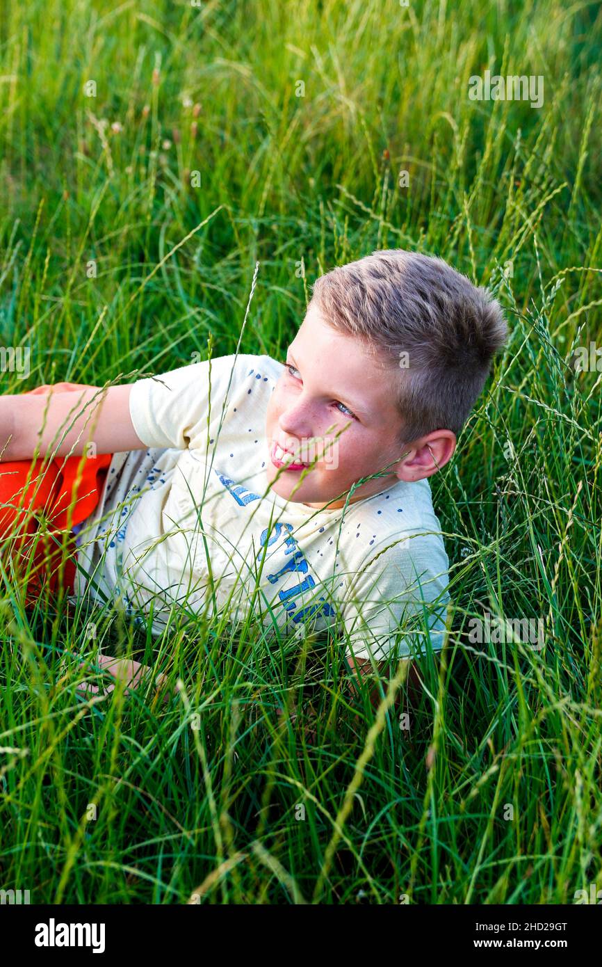 Kid boy lying on the green grass. Happy children in casual clothes ...