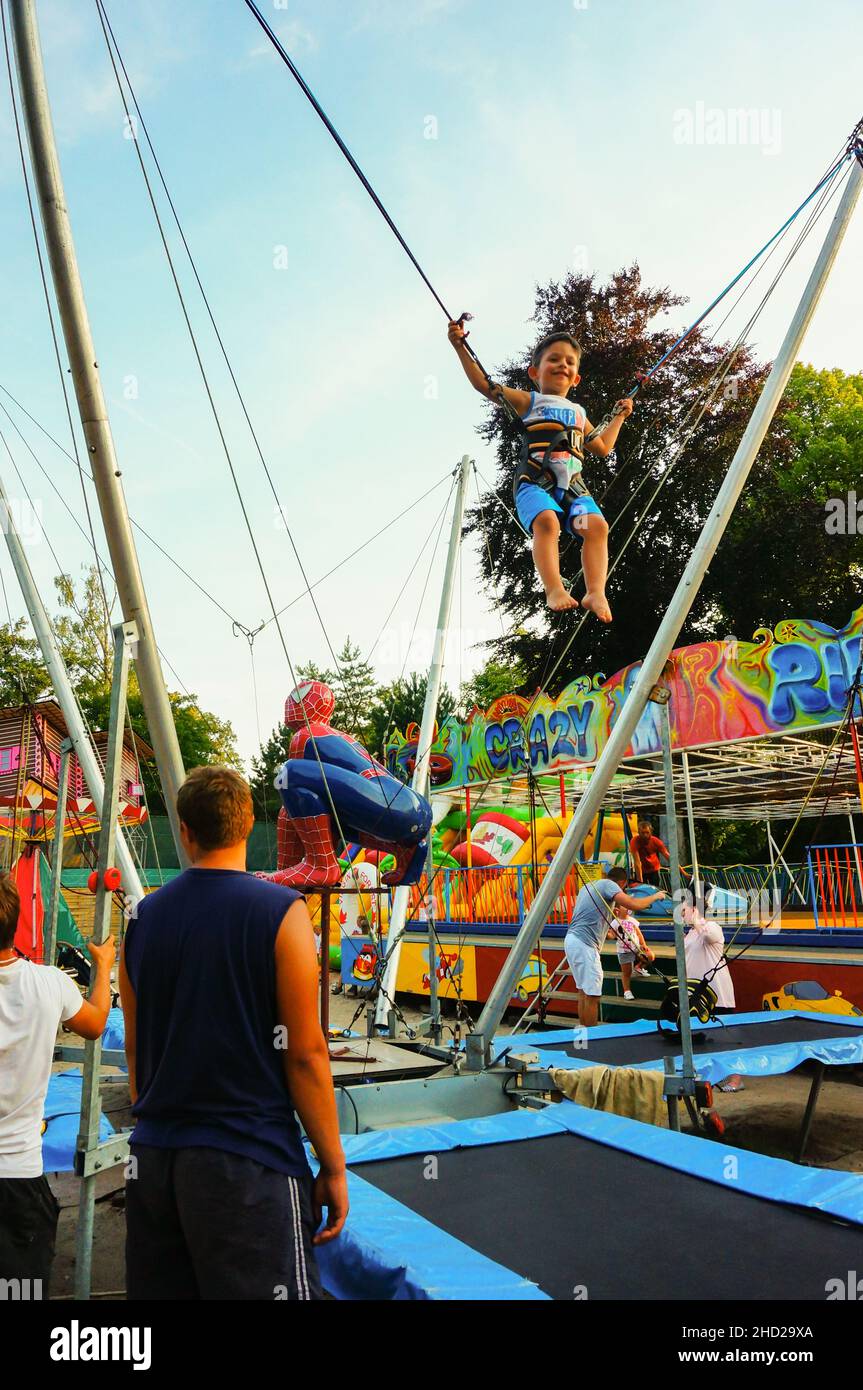 Vertical of a young boy jumping on a trampoline with safety lines in an ...