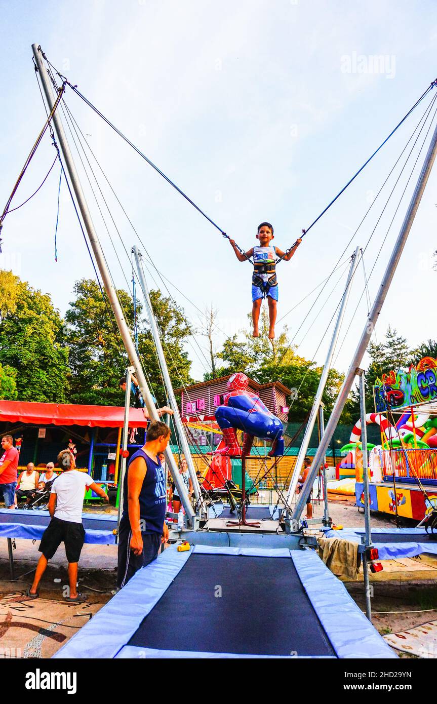 Vertical of a young boy jumping on a trampoline with safety lines in an ...