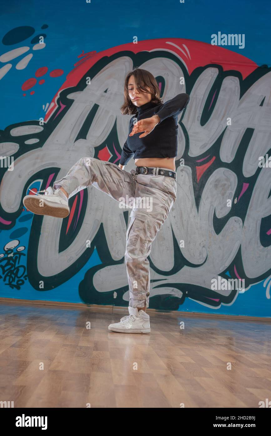Attractive young woman doing breakdance move over graffiti background ...