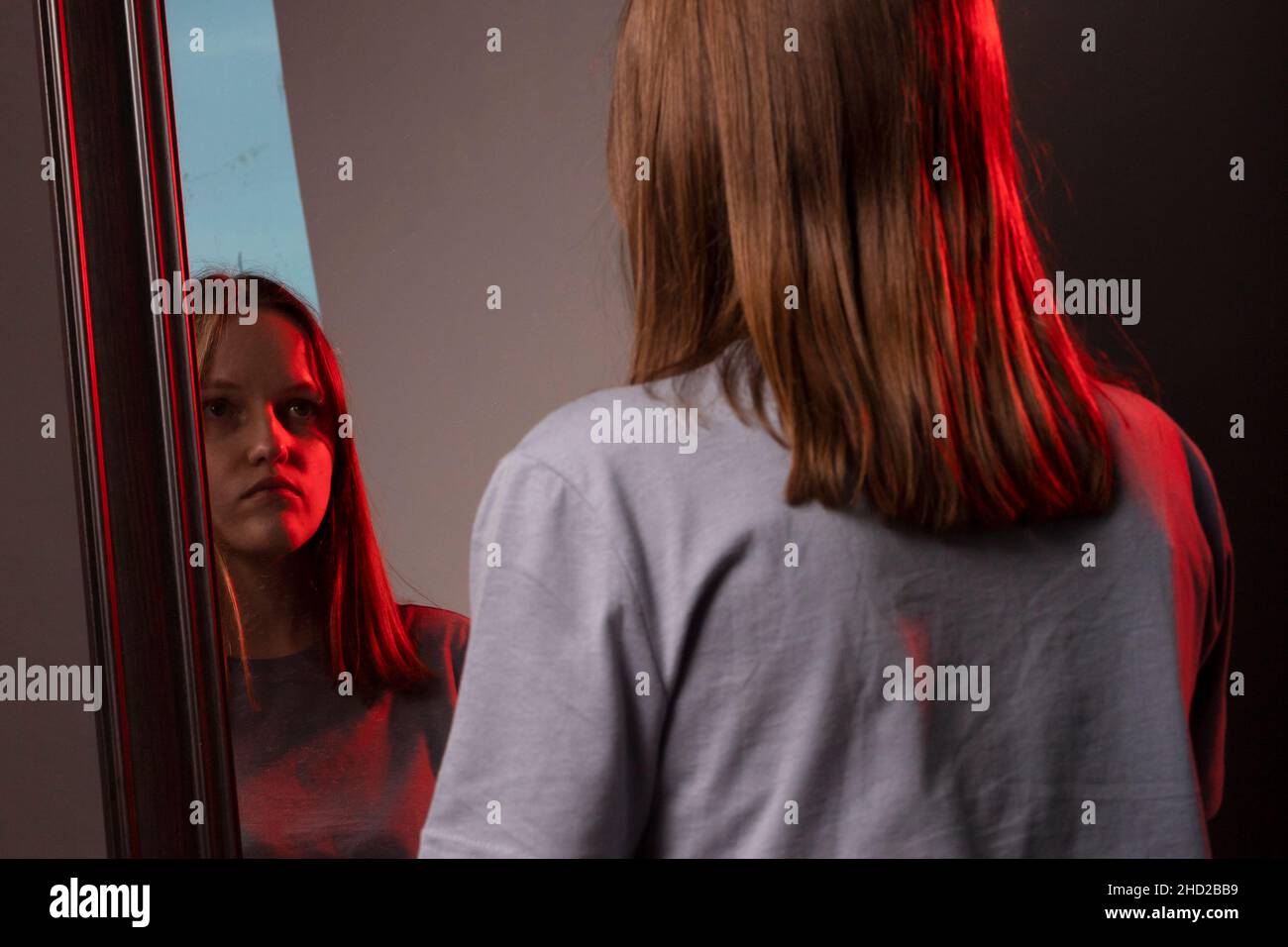 Young woman looking at her mirror reflection with grief. Unhappy sad ...