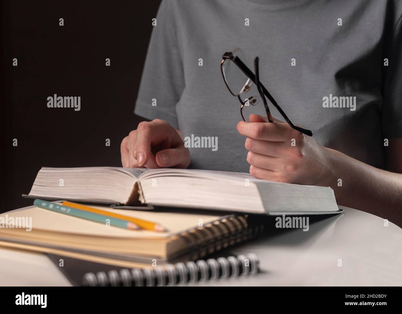 Female student hands close up, holding eyeglasses and book or textbook ...